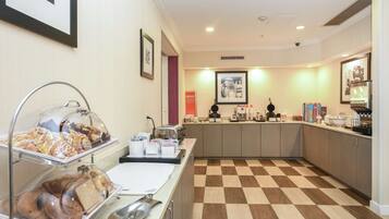 Uma área de buffet com diversos produtos de panificação e bebidas.
