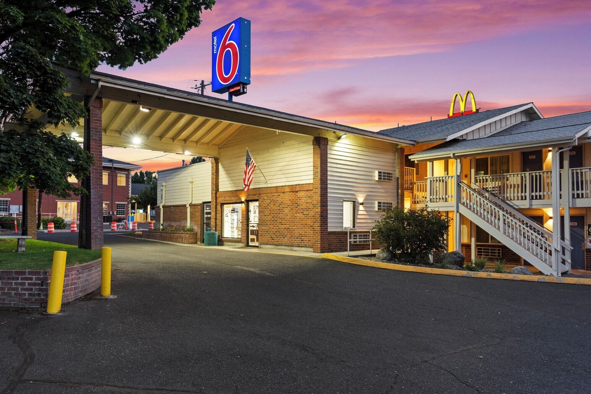 Um motel com um letreiro do McDonald's, uma área de estacionamento coberta e um edifício de dois andares com varanda.