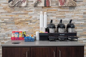 Uma cozinha com painel de backsplash de pedra, um espaço para café com produtos de marca e uma cafeteira Bunn.