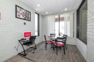 Espaço de negócios com mesa de computador, cadeiras e placa indicando Wi-Fi gratuito.