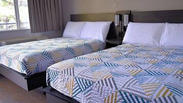 Quarto de hotel com duas camas, cada uma com colcha estampada e almofadas brancas.