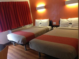 Quarto de hotel com duas camas, cortinas vermelhas, aquecedor e telefone na mesinha de cabeceira.