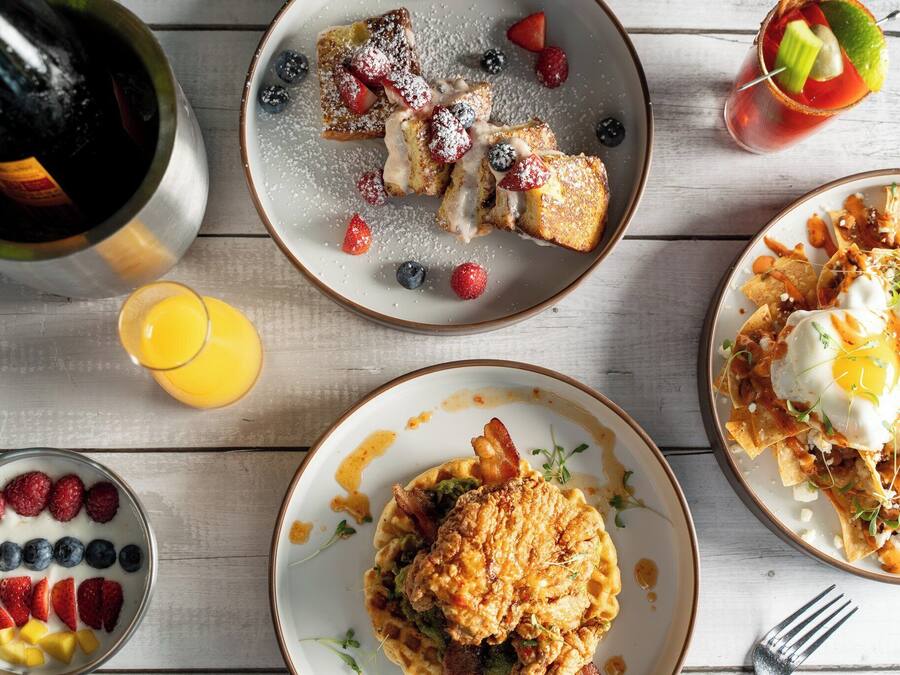 Uma mesa de café da manhã com diversos pratos, incluindo panquecas, ovos e frutas.