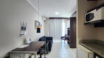 Um espaço compacto com cozinha compacta, área de jantar com mesa e cadeiras, e um sofá.