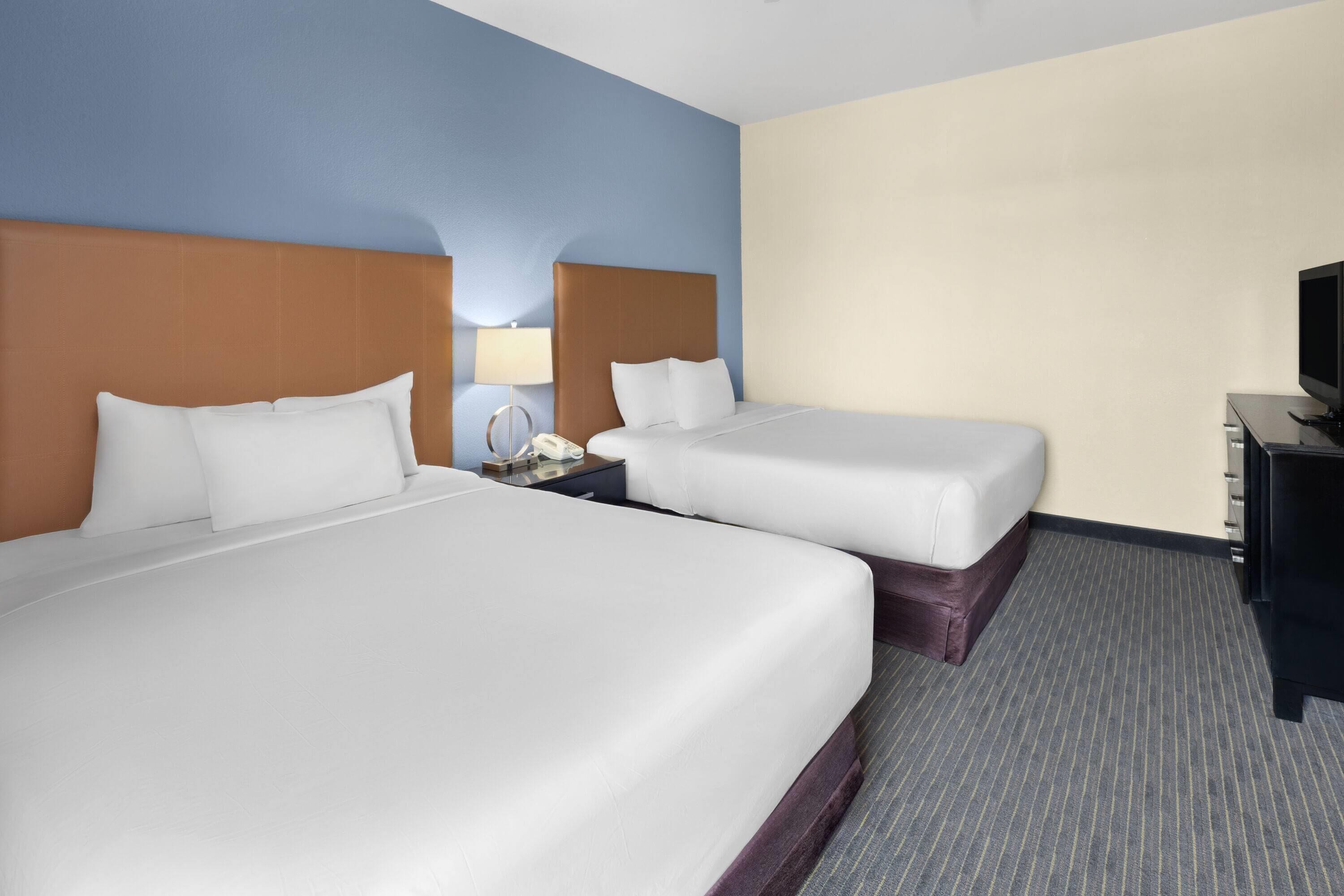 Quarto de hotel com duas camas, televisão e secretária.