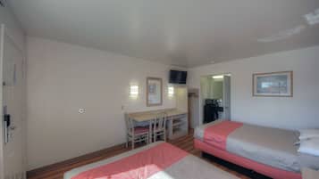 Quarto com duas camas, uma escrivaninha, uma cadeira, televisão e um quadro na parede.