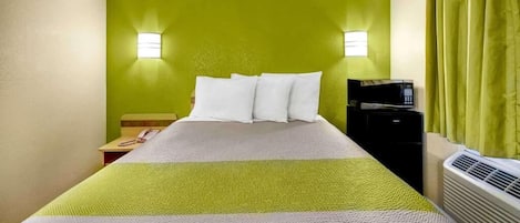 Quarto de hotel com cama, mesa de cabeceira, micro-ondas e ar condicionado.