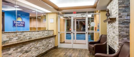 Um saguão com a placa Days Inn Suites, uma mesa de recepção, área de piscina e poltronas de couro.