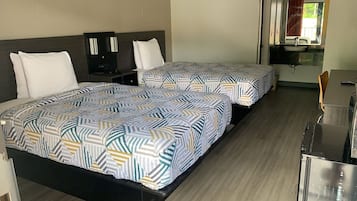 Quarto de hotel com duas camas, uma escrivaninha, uma cadeira, um espelho e uma janela.