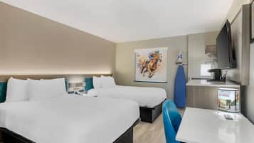 Quarto de hotel com duas camas, uma escrivaninha, televisão e um quadro na parede.