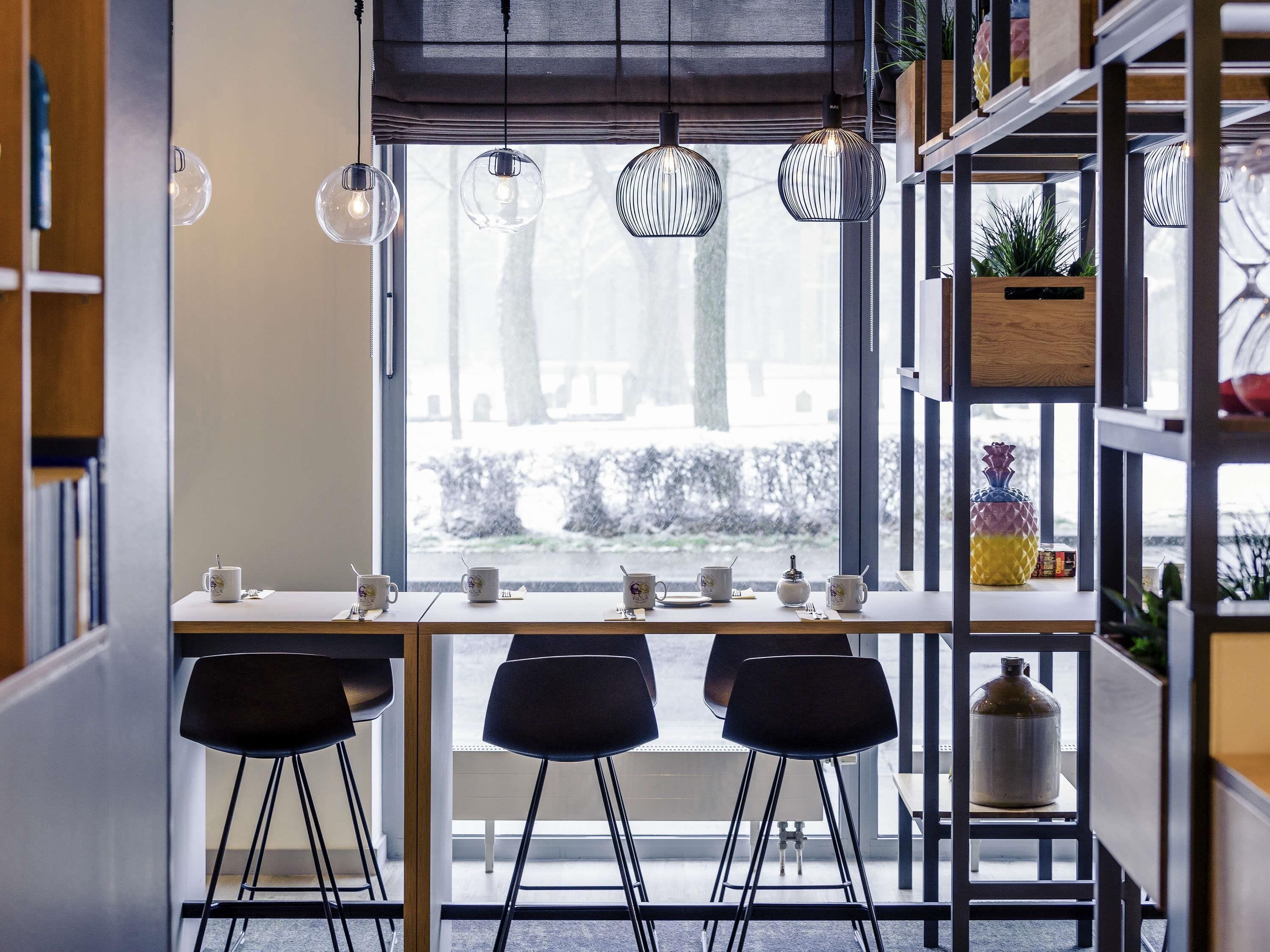 Cozinha moderna com mesa de jantar, cadeiras, luminárias pendentes e vista para o exterior.