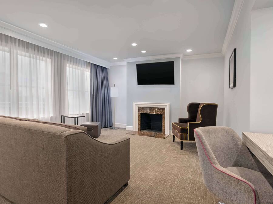 Uma sala de estar moderna com sofá, poltrona, lareira, televisão de tela plana e uma mesa.