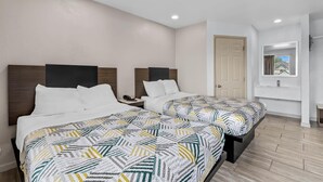 Quarto de hotel com duas camas, uma mesa de cabeceira, um espelho e uma porta.