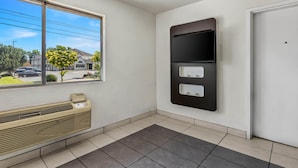 Quarto de hotel com uma janela grande, ar condicionado fixado na parede e uma porta.