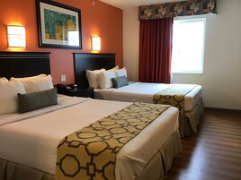 Quarto de hotel com duas camas, um quadro na parede e uma janela com cortinas.