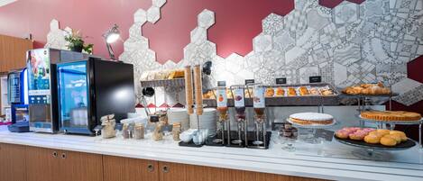 Um buffet de café da manhã com diversos alimentos, uma máquina de café e um dispensador de sucos.