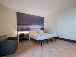 Quarto de hotel com uma cama, uma mesa e uma cadeira.
