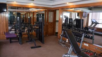 Uma academia com diversos equipamentos de exercício, espelhos e painéis de madeira.