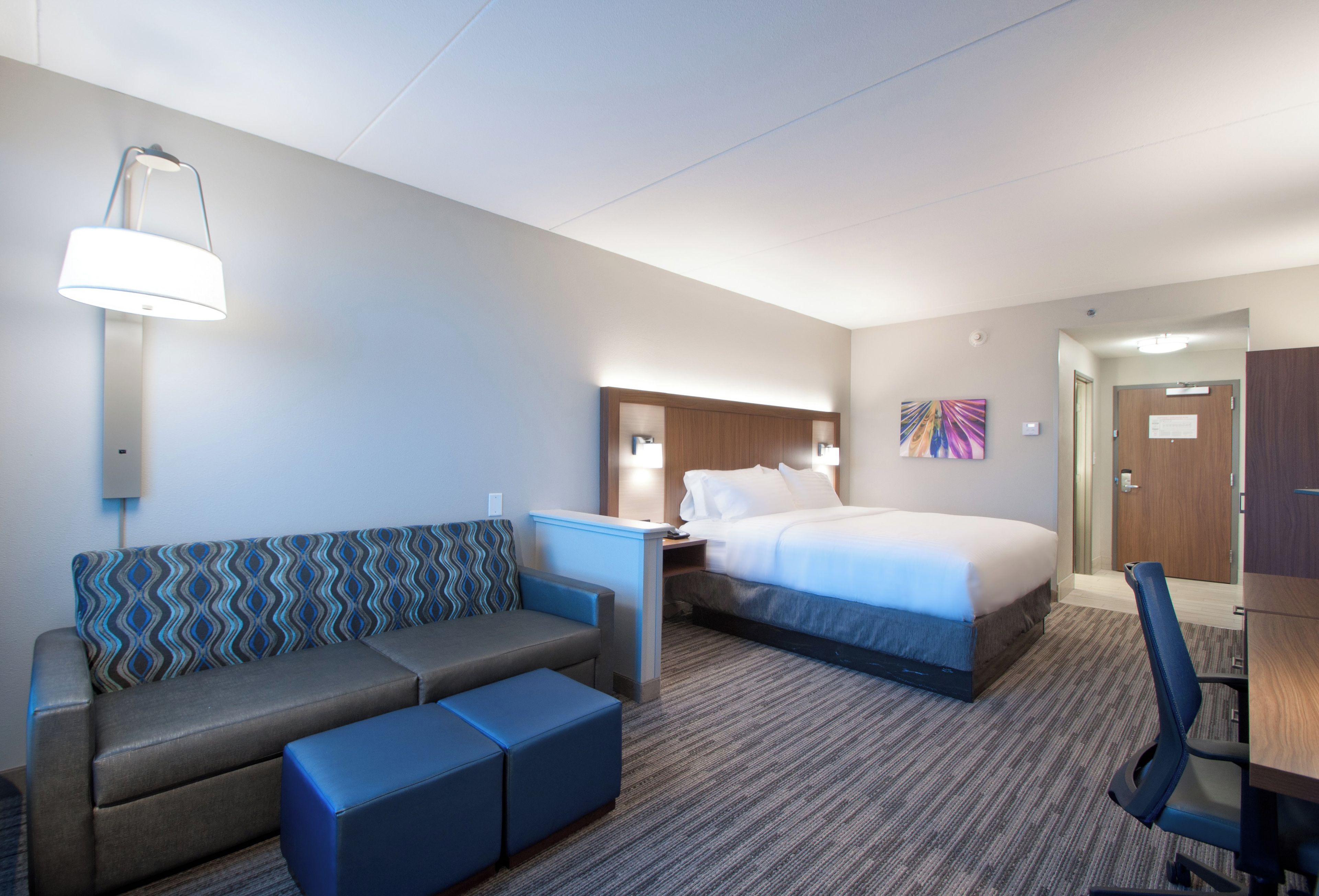 Quarto de hotel com cama, sofá, escrivaninha e cadeira.