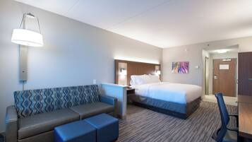 Quarto de hotel com cama, sofá, escrivaninha e cadeira.