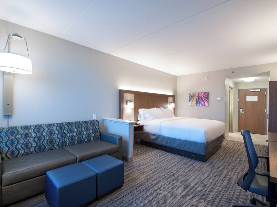 Quarto de hotel com cama, sofá, escrivaninha e cadeira.