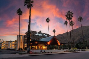Hotel com placa chamativa indicando 'Royal Sun' contra um céu ao pôr do sol.