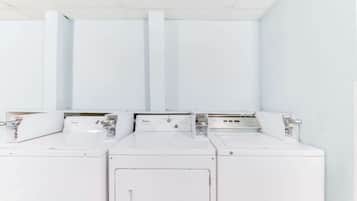 Uma lavanderia com três máquinas de lavar e secar Whirlpool brancas.