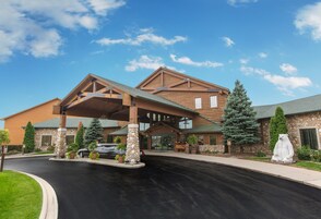 Um amplo edifício em estilo cabana de madeira com entrada coberta, pilares de pedra e plantas em vasos.