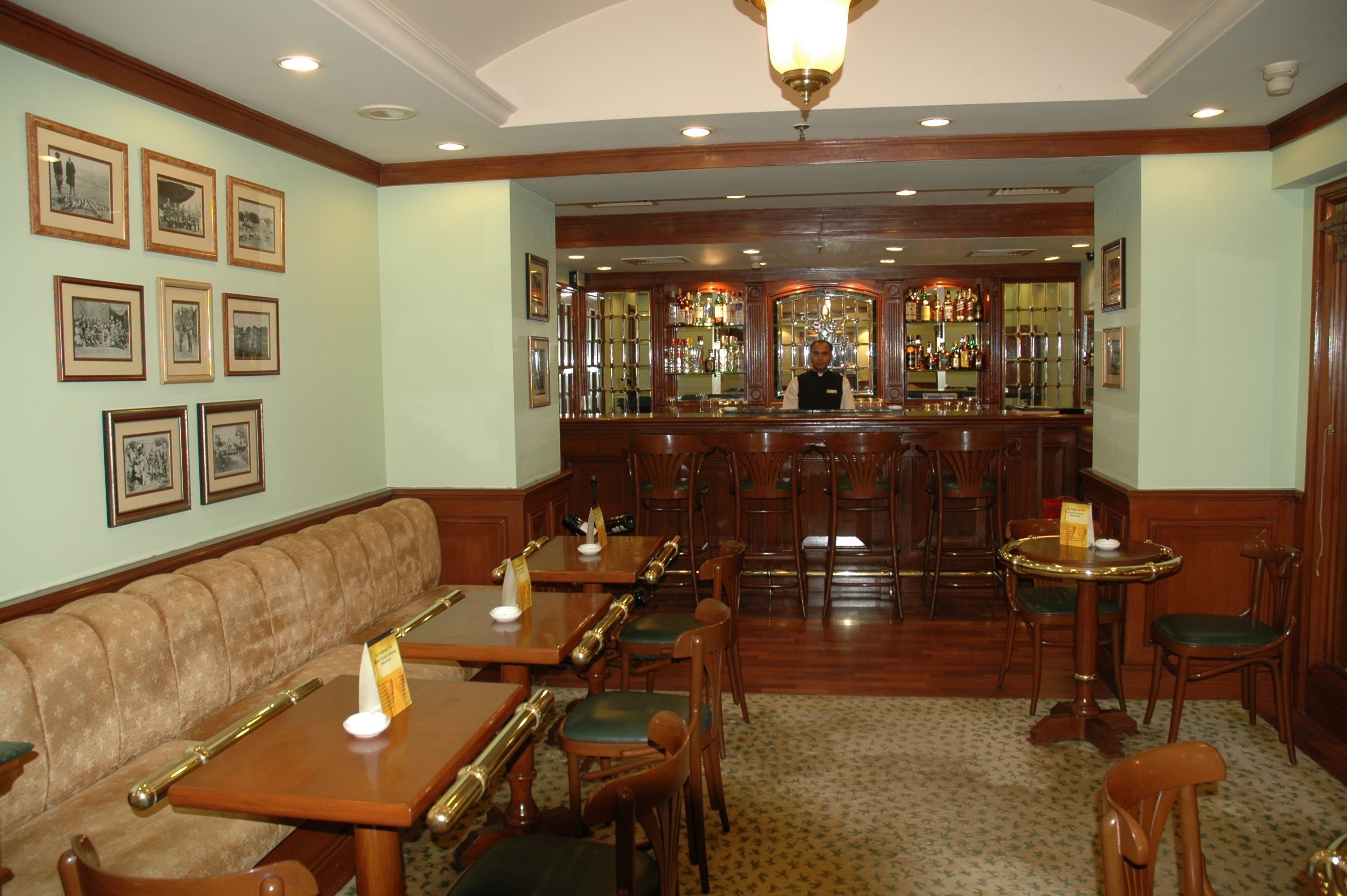 Uma área de bar com mobiliário de madeira, balcão e quadros na parede.