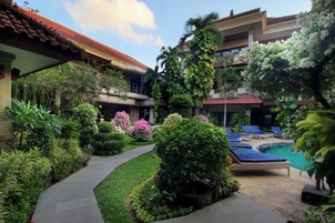 Um pátio com piscina, espreguiçadeiras e vegetação exuberante.