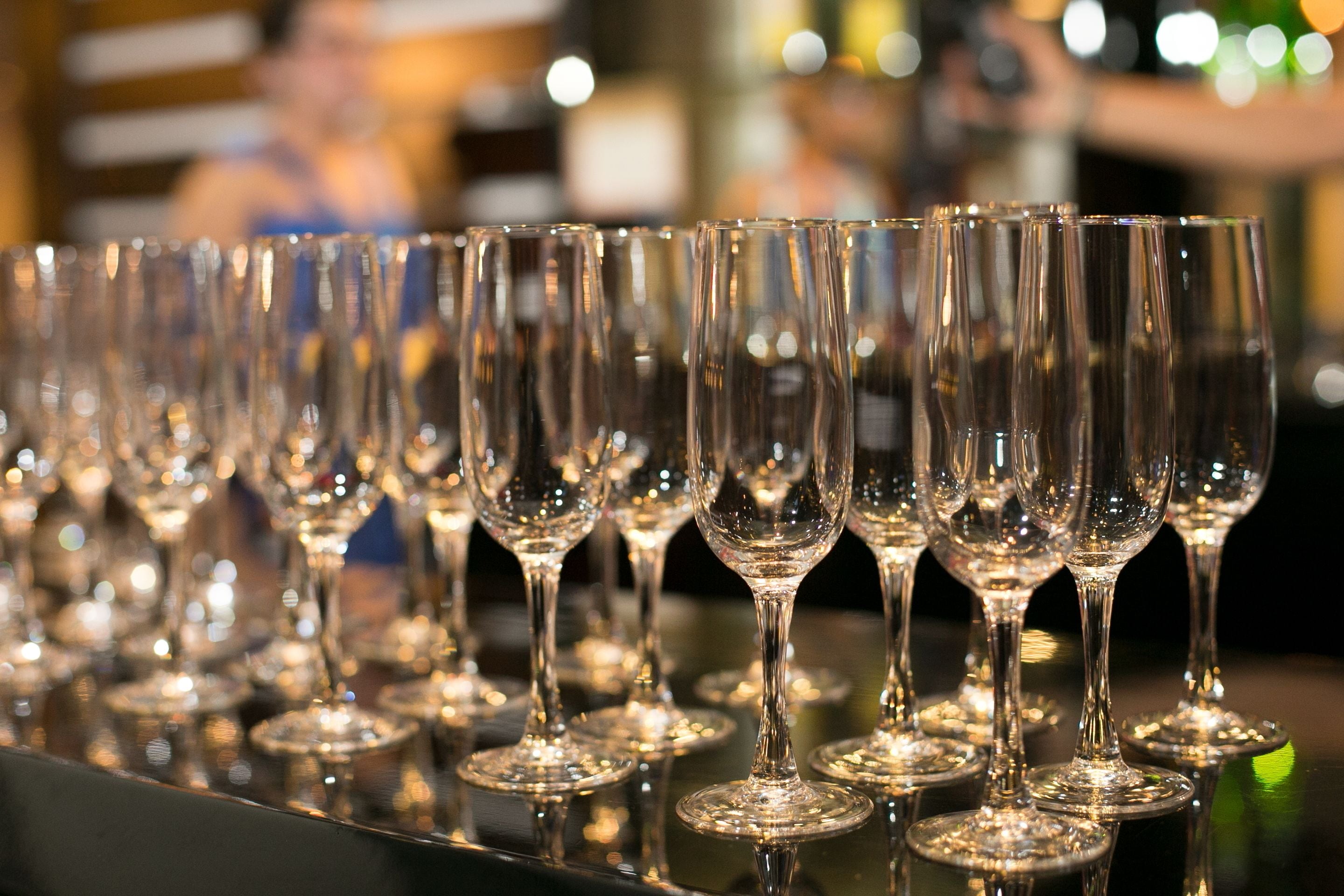 Vários copos de vinho vazios em uma superfície espelhada.