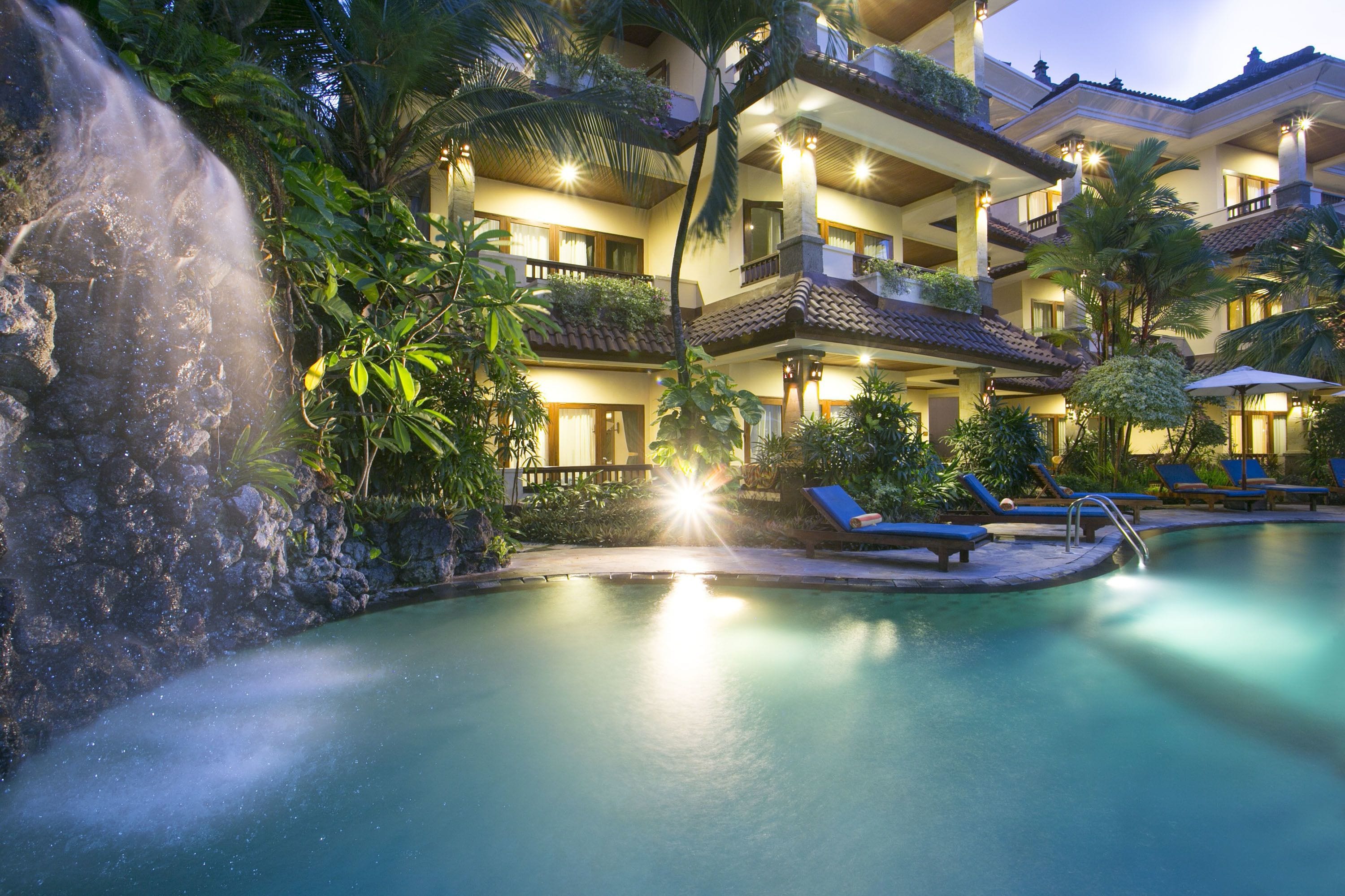 Hotel com piscina, espreguiçadeiras e uma cascata.