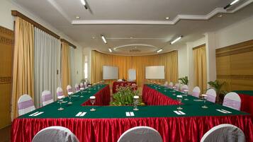 Sala de conferências com uma mesa comprida, cadeiras e toalha de mesa vermelha.