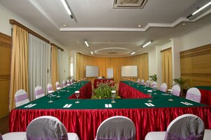 Sala de conferências com uma mesa comprida, cadeiras e toalha de mesa vermelha.