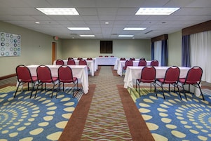 Sala de conferências com mesas e cadeiras dispostas para uma reunião.