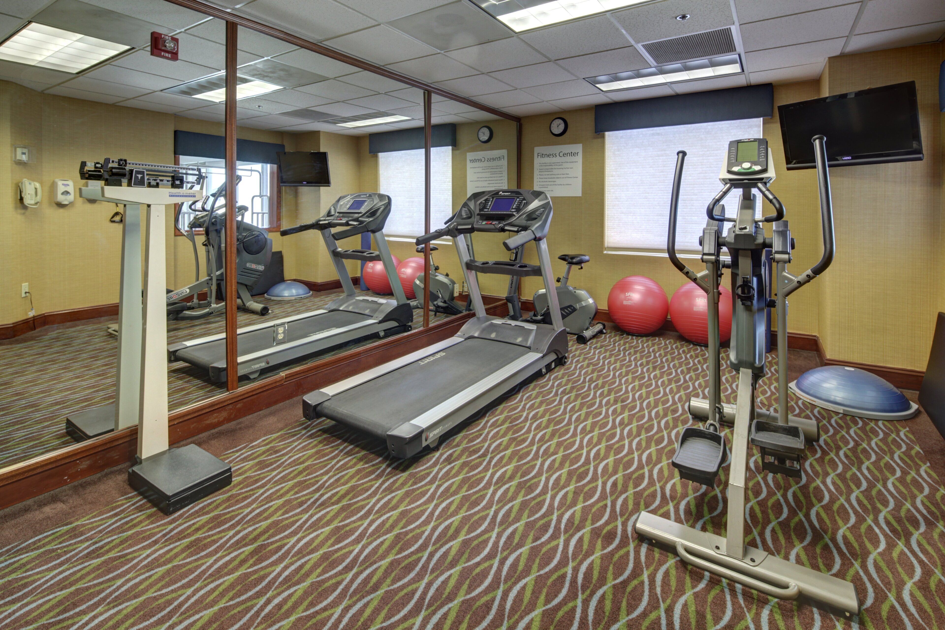 Centro de fitness com esteiras, elípticos e bolas de exercício.