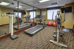 Centro de fitness com esteiras, elípticos e bolas de exercício.