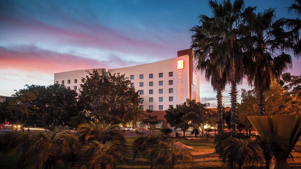 Um hotel com design moderno, exibindo uma placa grande com o nome 'Festa Inn' na lateral.