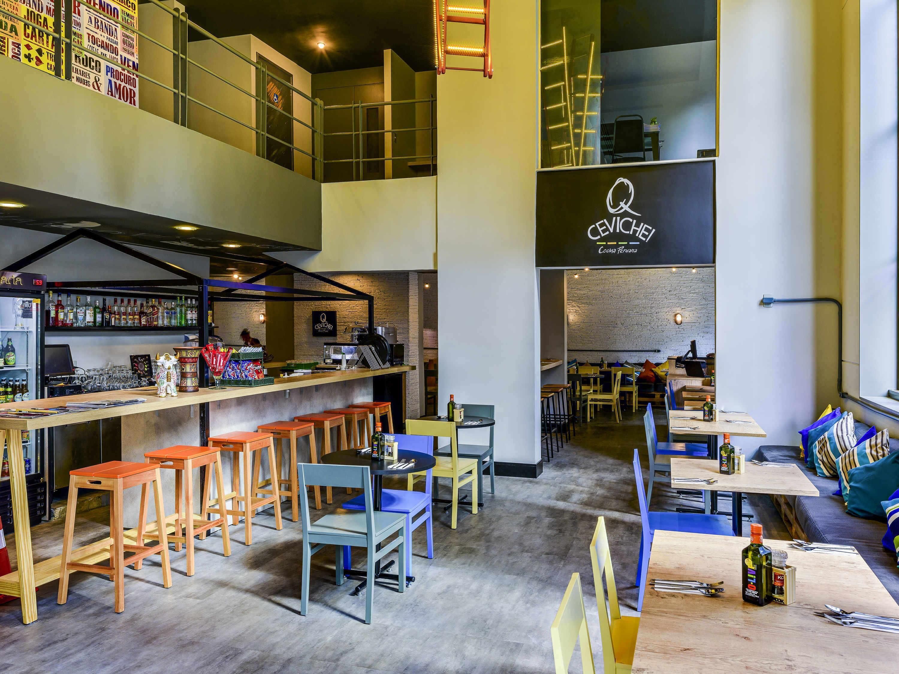 Uma área de bar moderna com banquetas, um balcão e diversas garrafas.