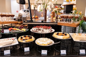 Buffet com diversas sobremesas e bebidas, incluindo bolos, tortas e frutas.