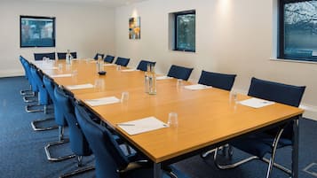 Uma sala de conferência com uma mesa comprida, cadeiras e uma tela de projetor.