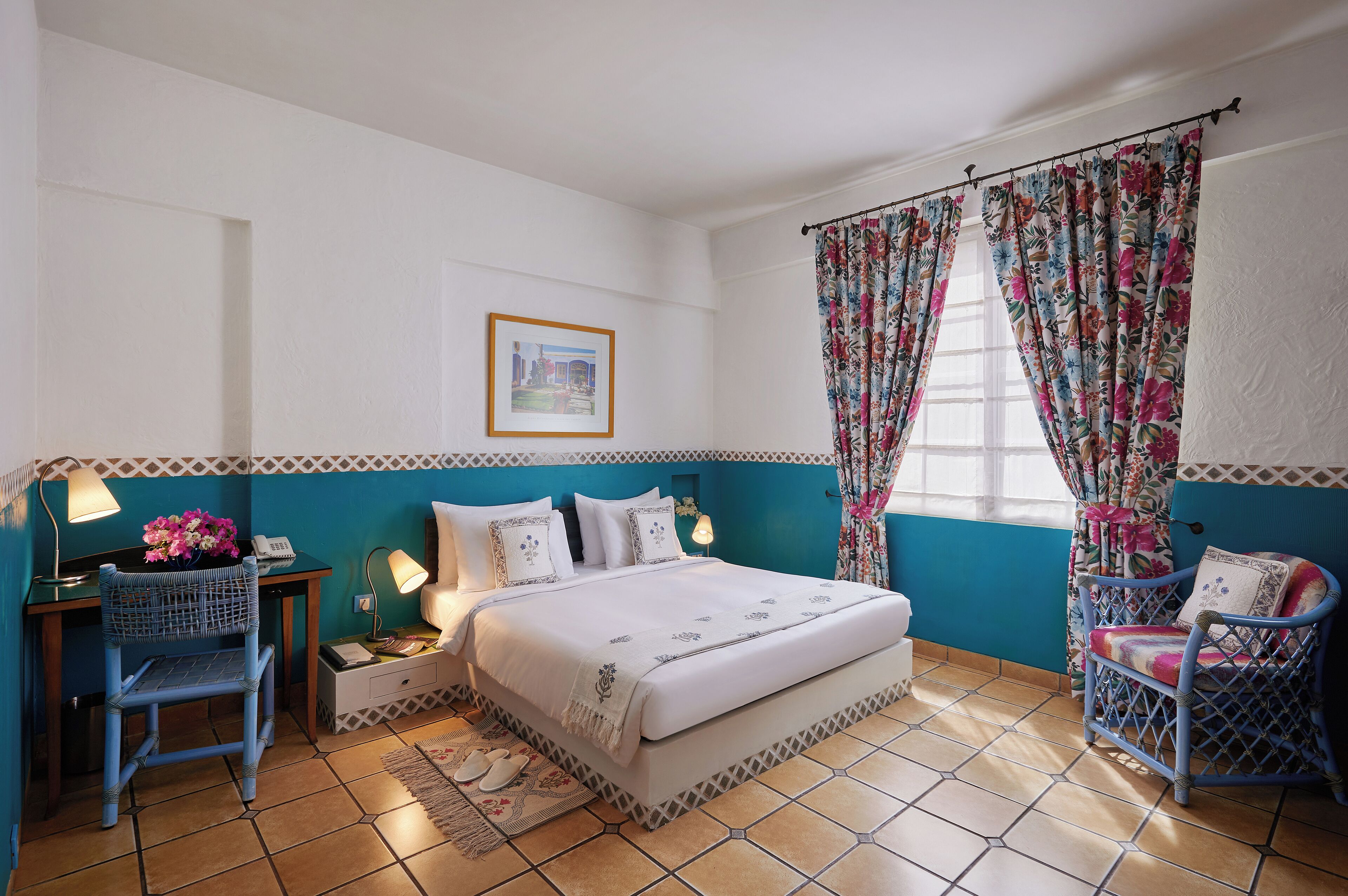 Quarto com cama, escrivaninha, cadeira e janela com cortinas.