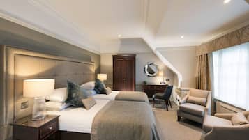 Quarto de hotel com uma cama grande, mesas de cabeceira, escrivaninha e uma cadeira.