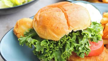 Um prato com sanduíche, batatas fritas e hambúrguer.