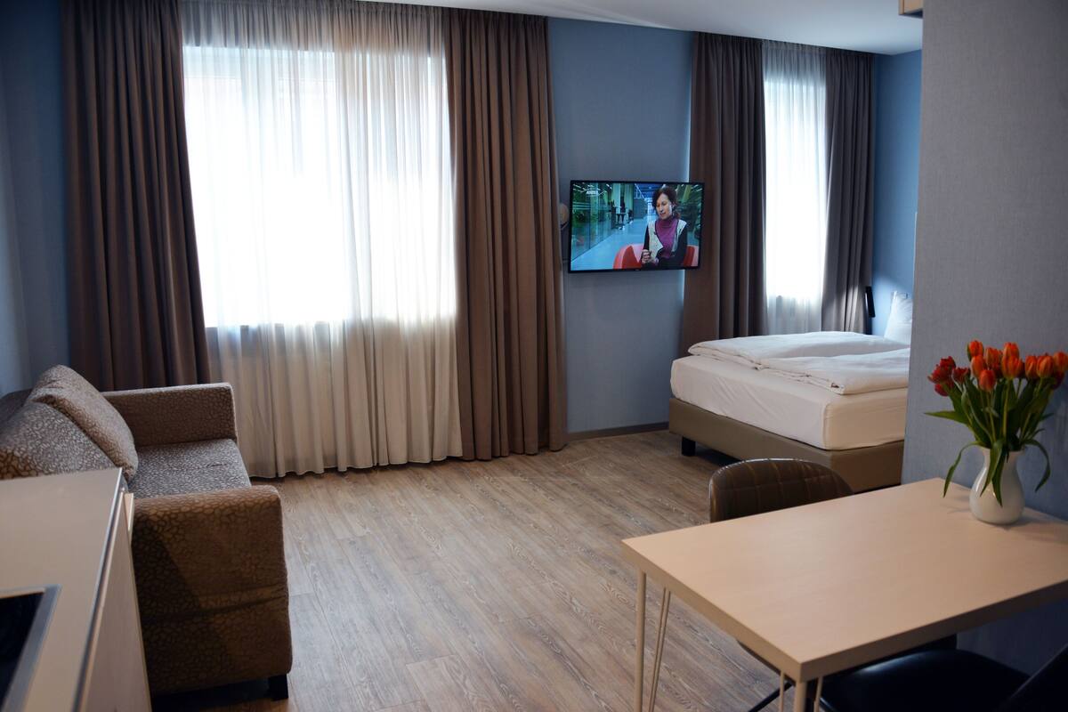 Quarto de hotel com uma cama, um sofá, uma televisão e uma mesa.