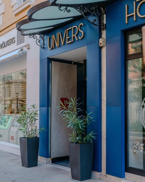 Entrada de um hotel com uma placa que diz 'UNIVERS'.