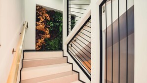 Uma escadaria com design moderno, com guarda-corrimão de vidro e uma parede com jardim vertical.