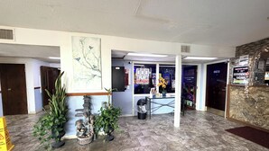 Um saguão com balcão de recepção, pintura de pássaros e estátua de criança.