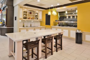 Cozinha moderna com ilha central, banquetas e iluminação pendente.
