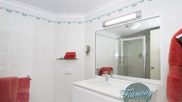 Um banheiro com azulejos brancos, um espelho grande, uma pia e duas toalhas vermelhas.